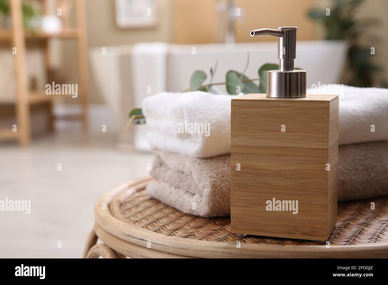 Wooden dispenser of liquid soap, clean towels and eucalyptus branch on ...