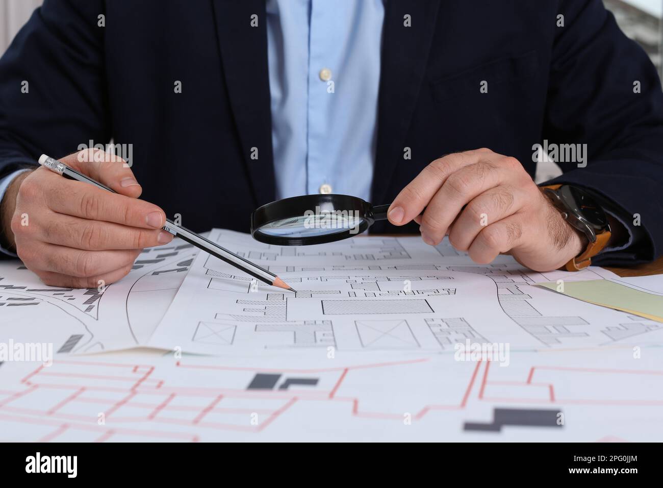 Professional cartographer working with cadastral map at table, closeup ...