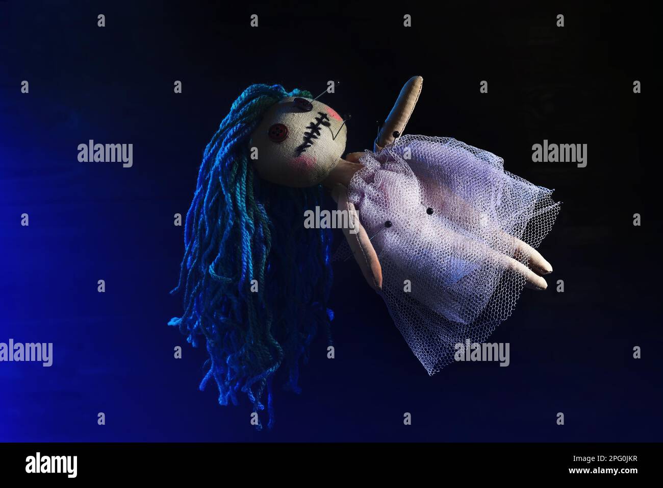 Female voodoo doll with pins on dark blue background Stock Photo - Alamy