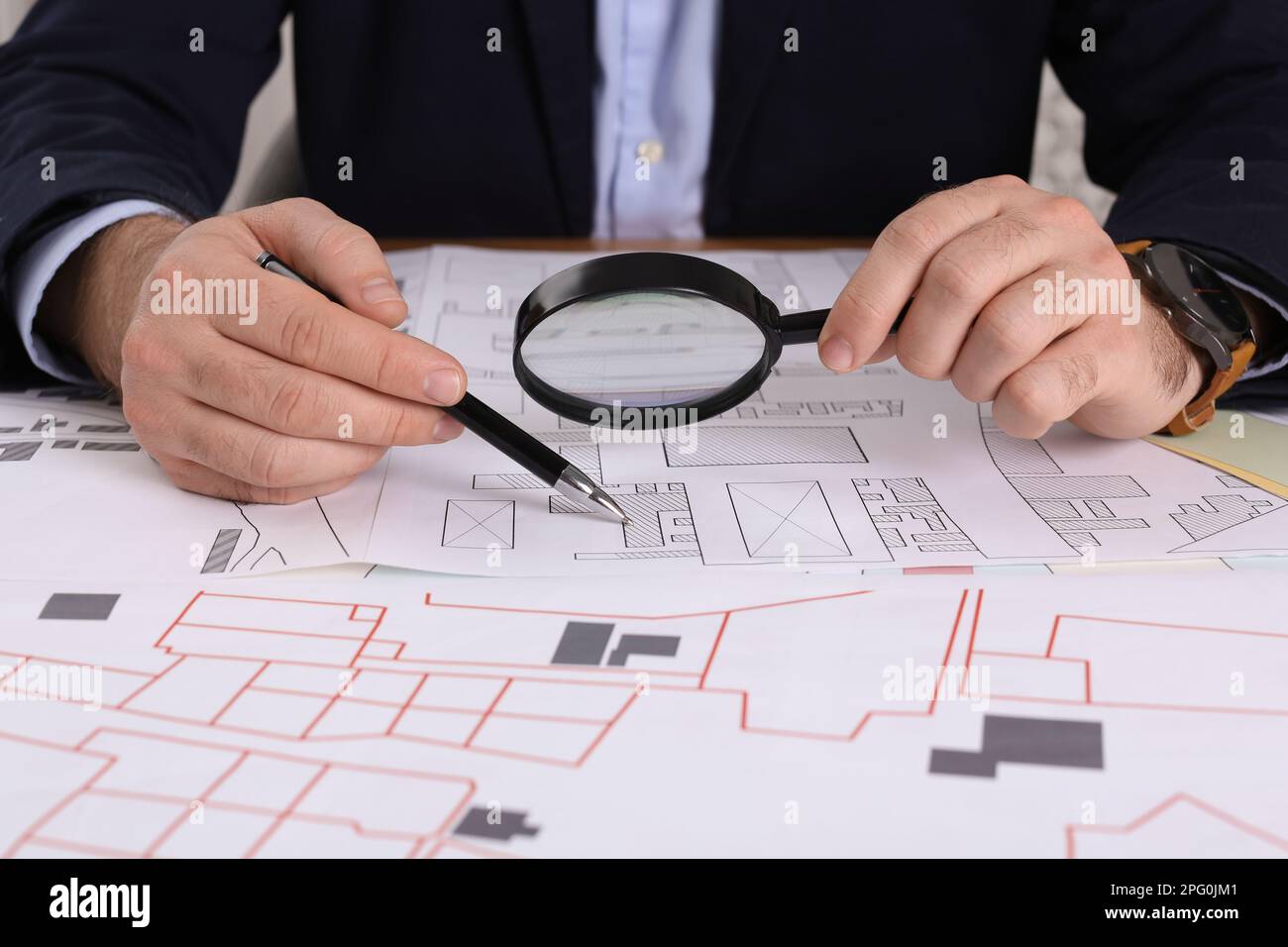 Professional cartographer working with cadastral map at table, closeup ...