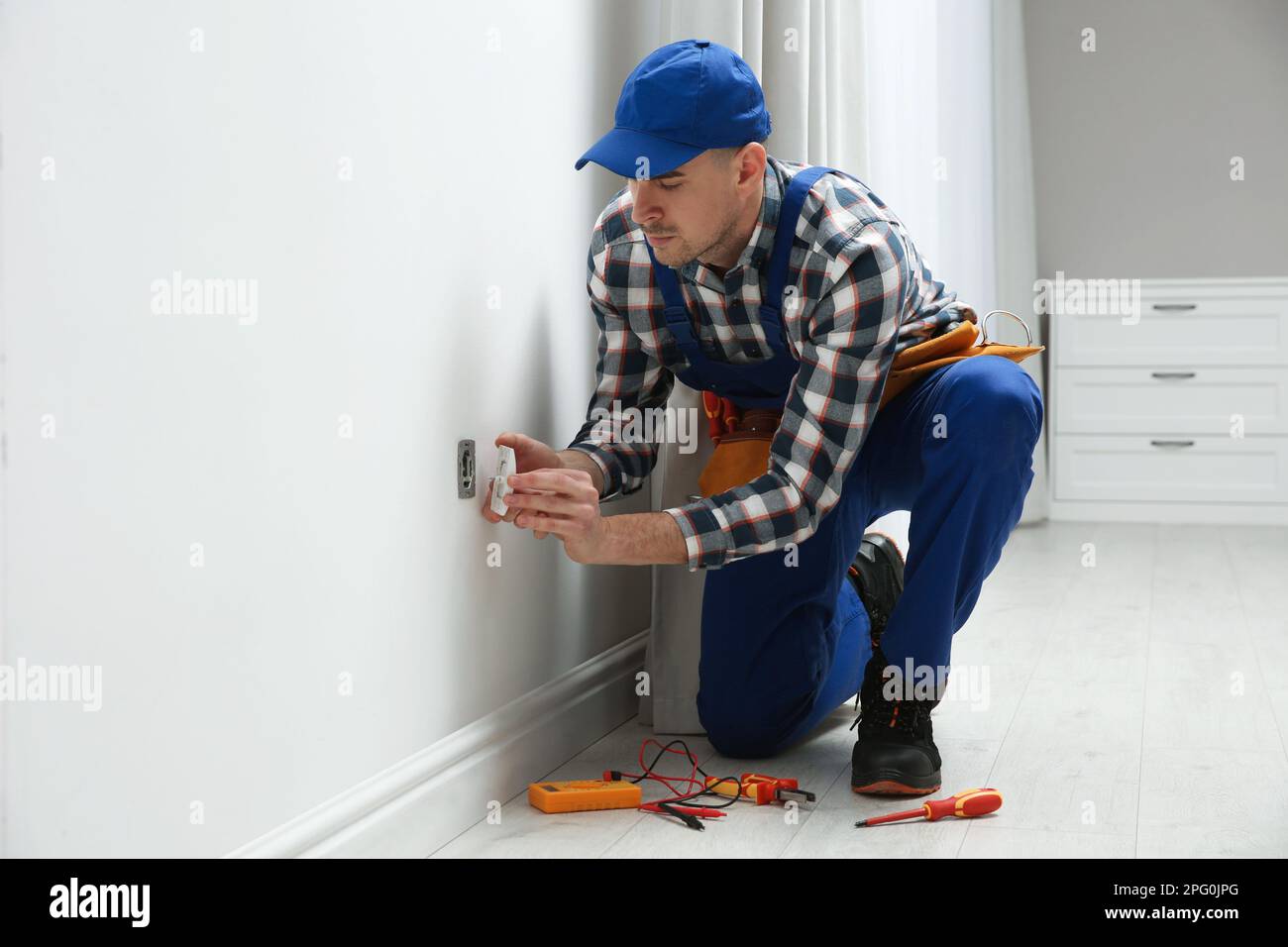 Professional male electrician repairing power socket in room Stock ...