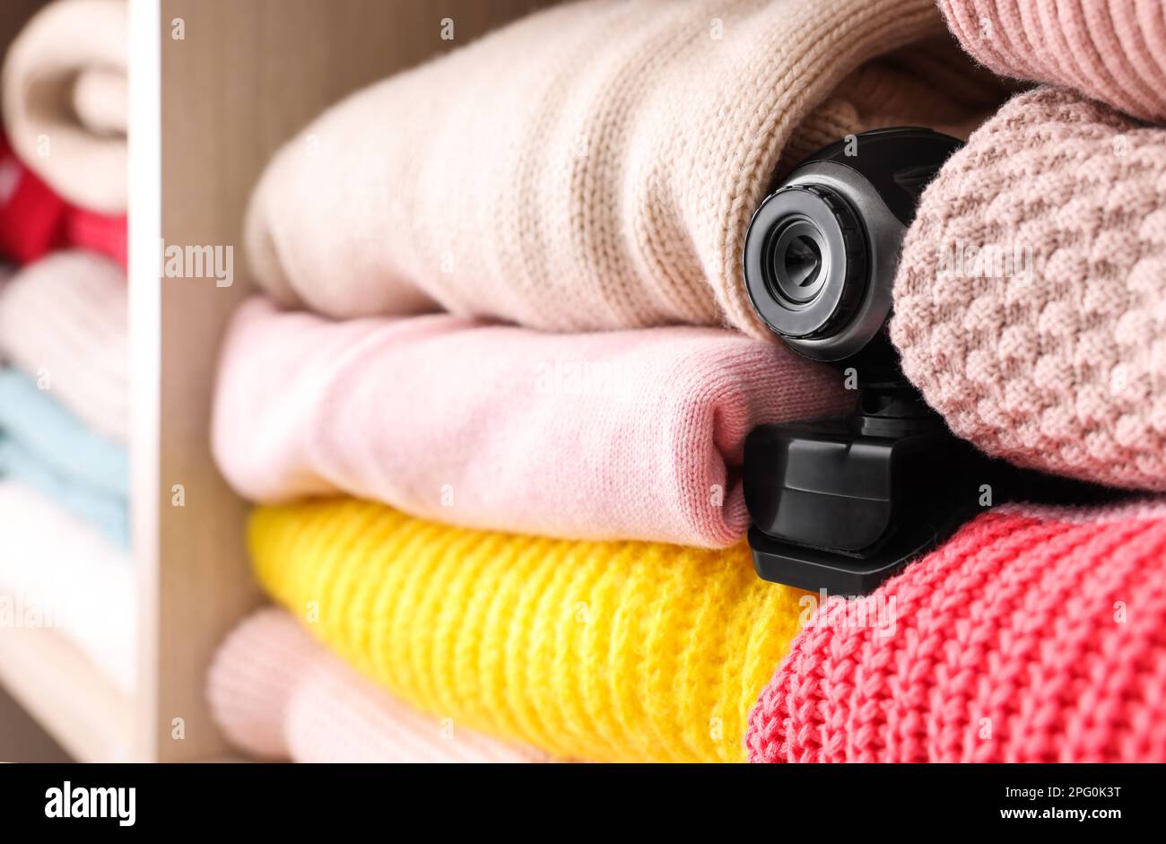 Camera hidden between clothes in wardrobe closet, closeup. Space for ...