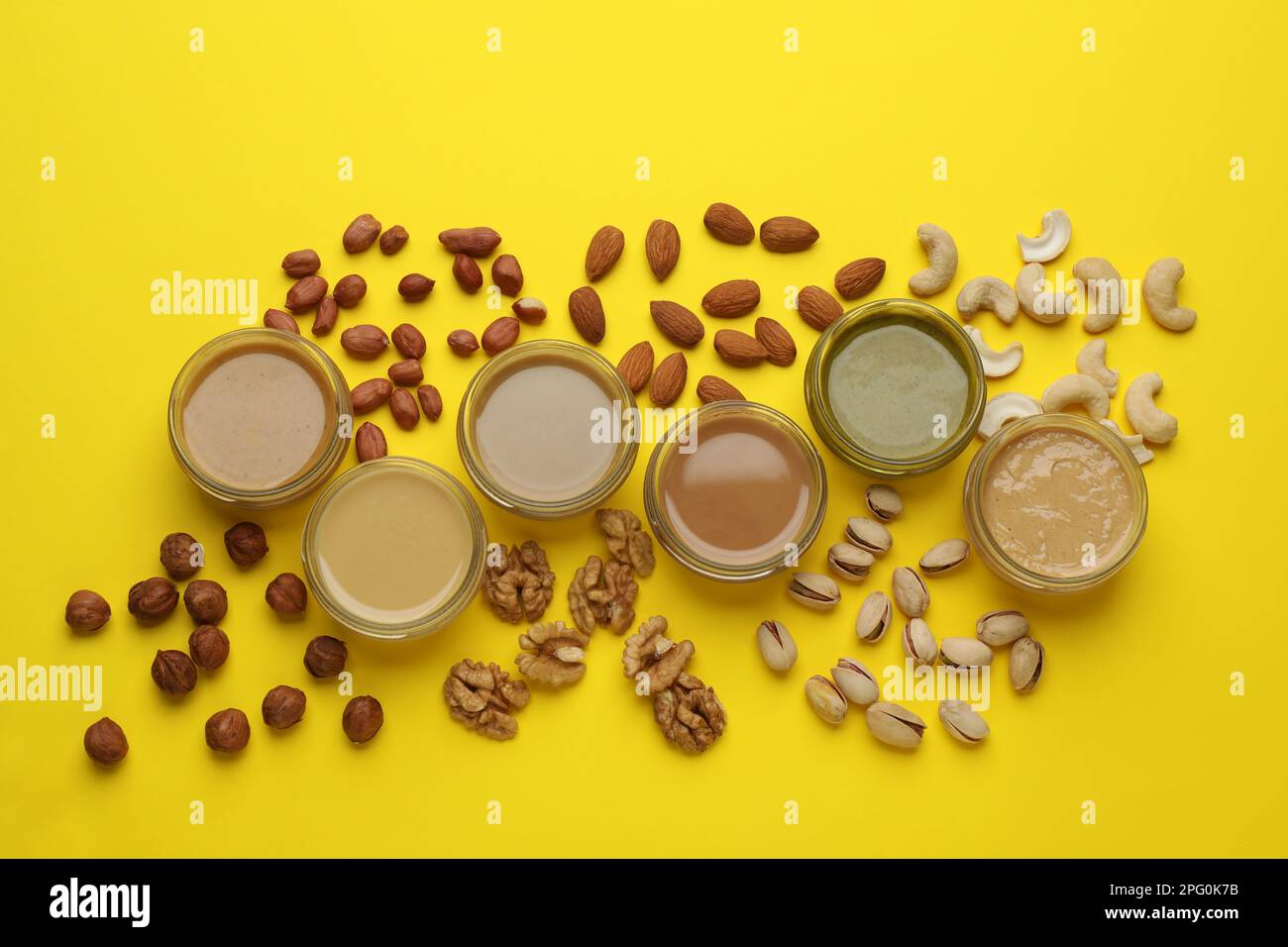 Different types of nut butter and ingredients on yellow background ...