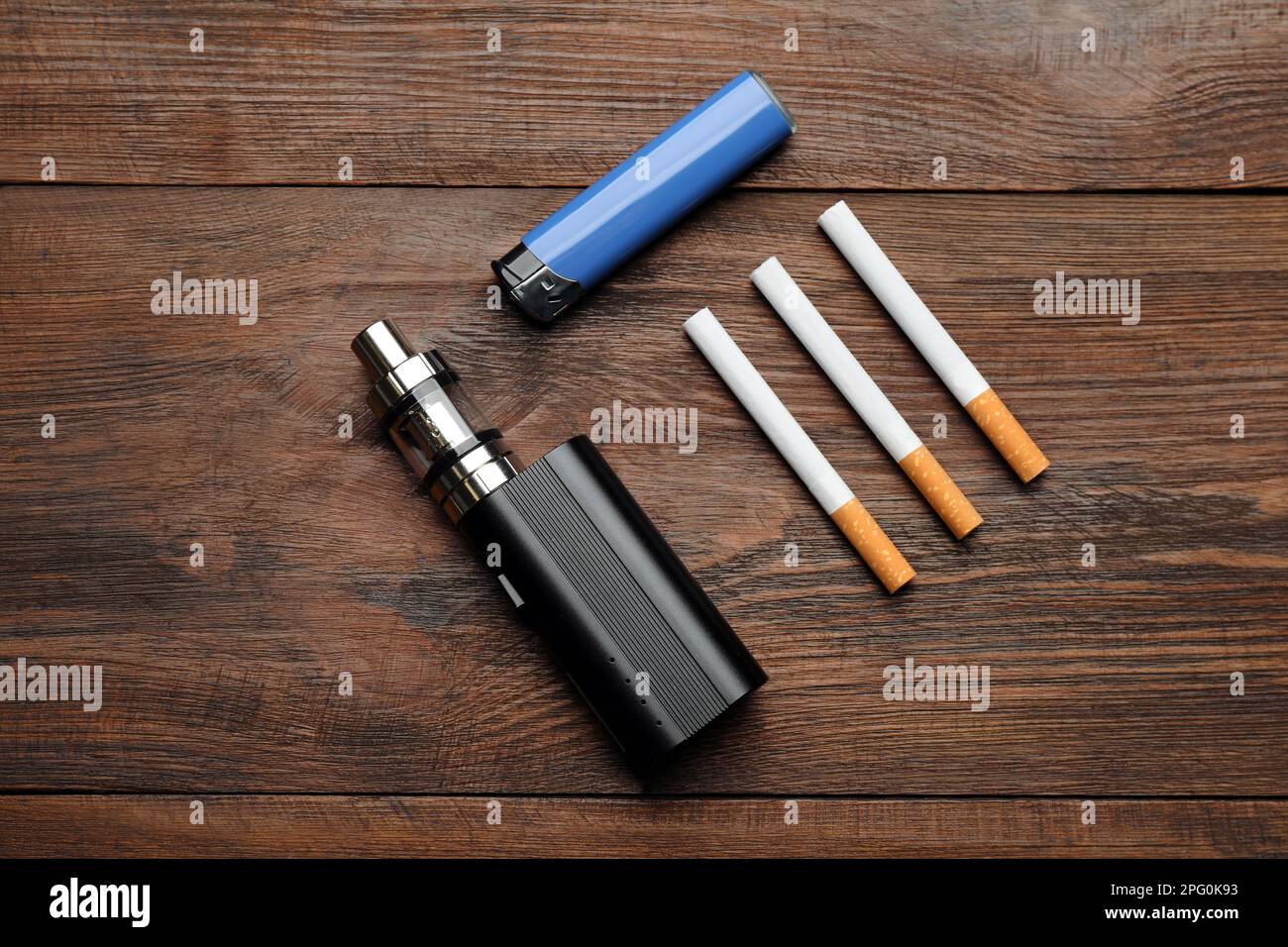 Cigarettes, lighter and vaping device on wooden background, flat lay ...