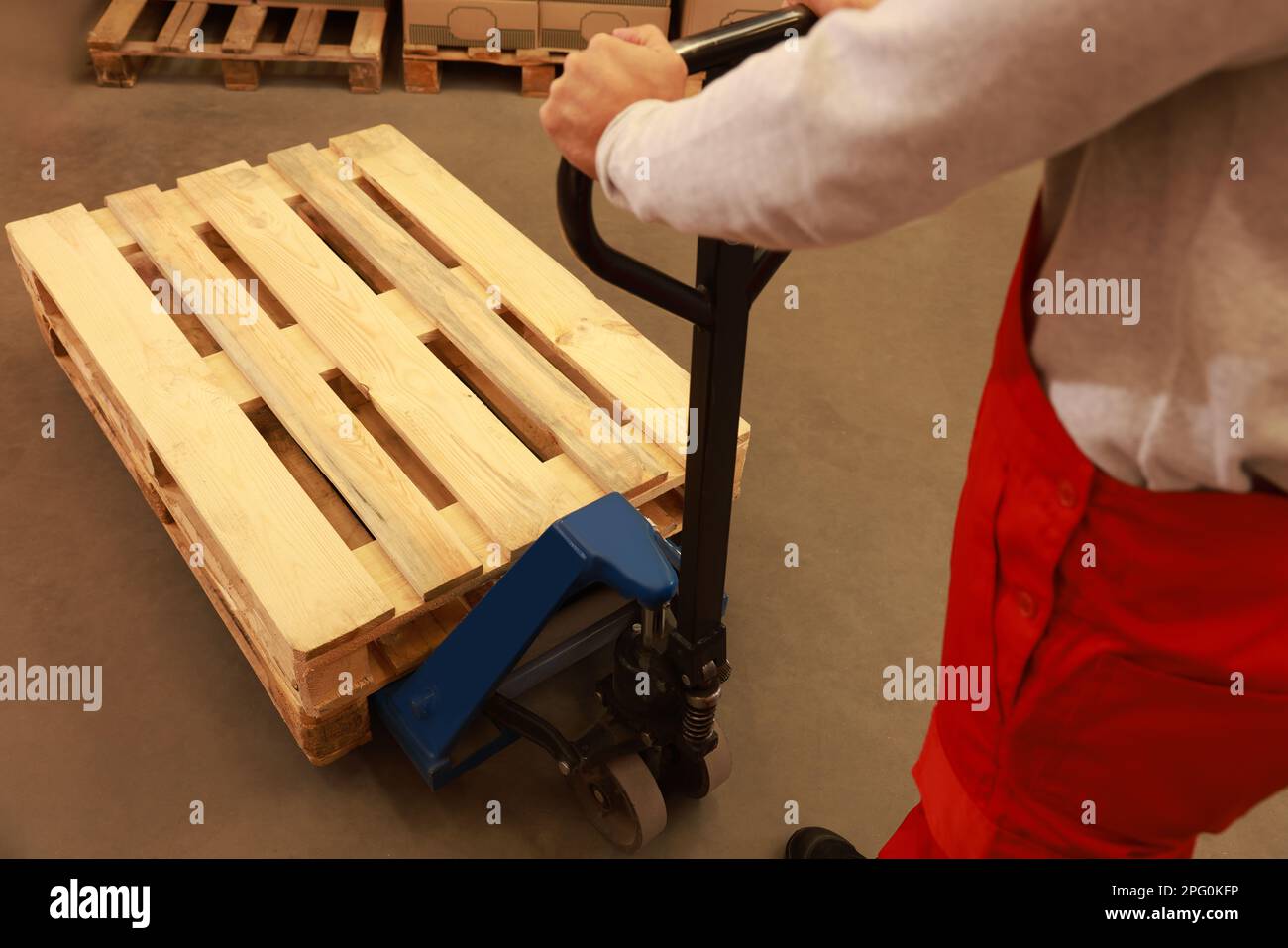 Worker moving wooden pallets with manual forklift in warehouse, closeup ...