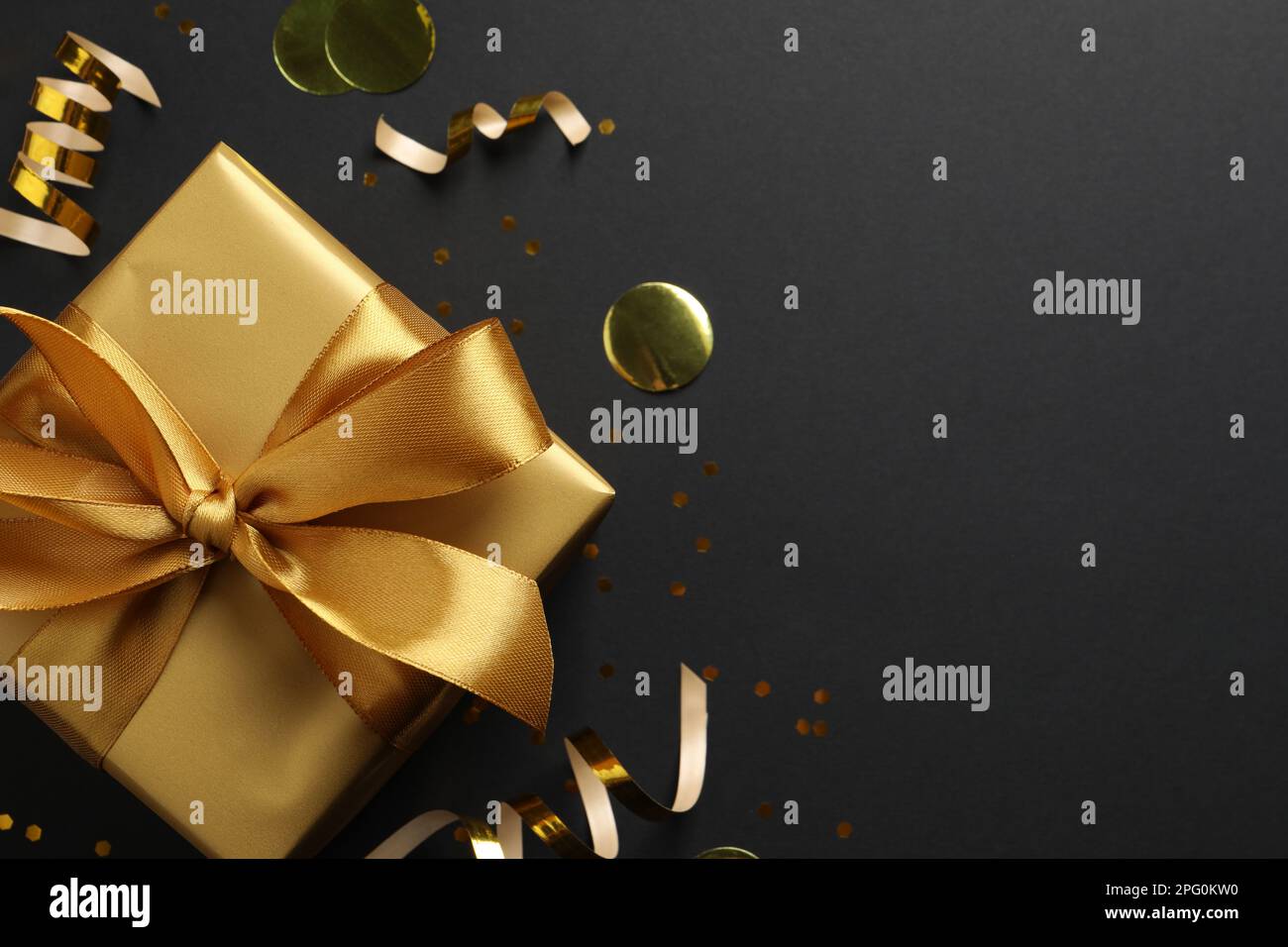 Golden gift box with confetti and streamers on black background, flat ...