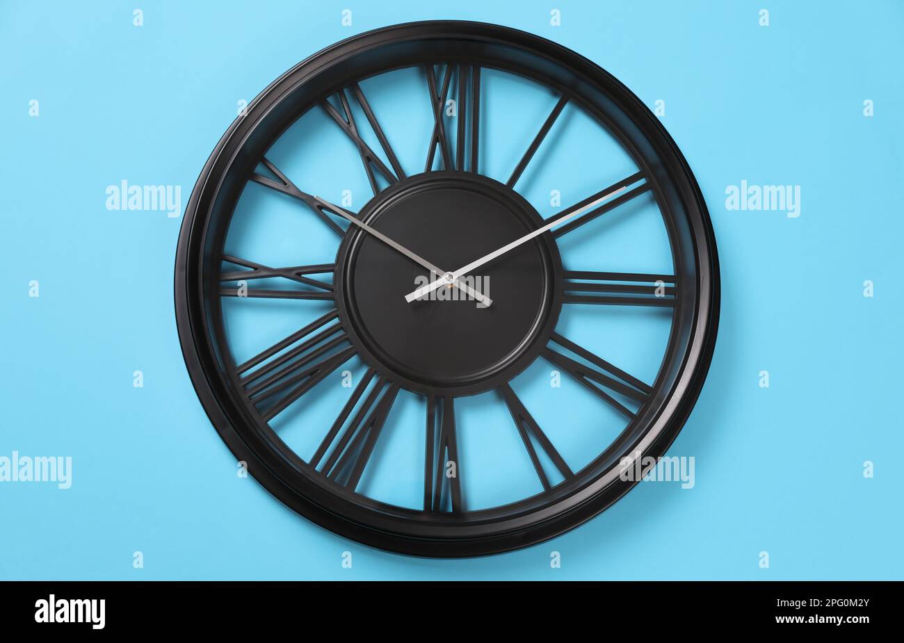 Stylish analog clock hanging on light blue wall Stock Photo - Alamy