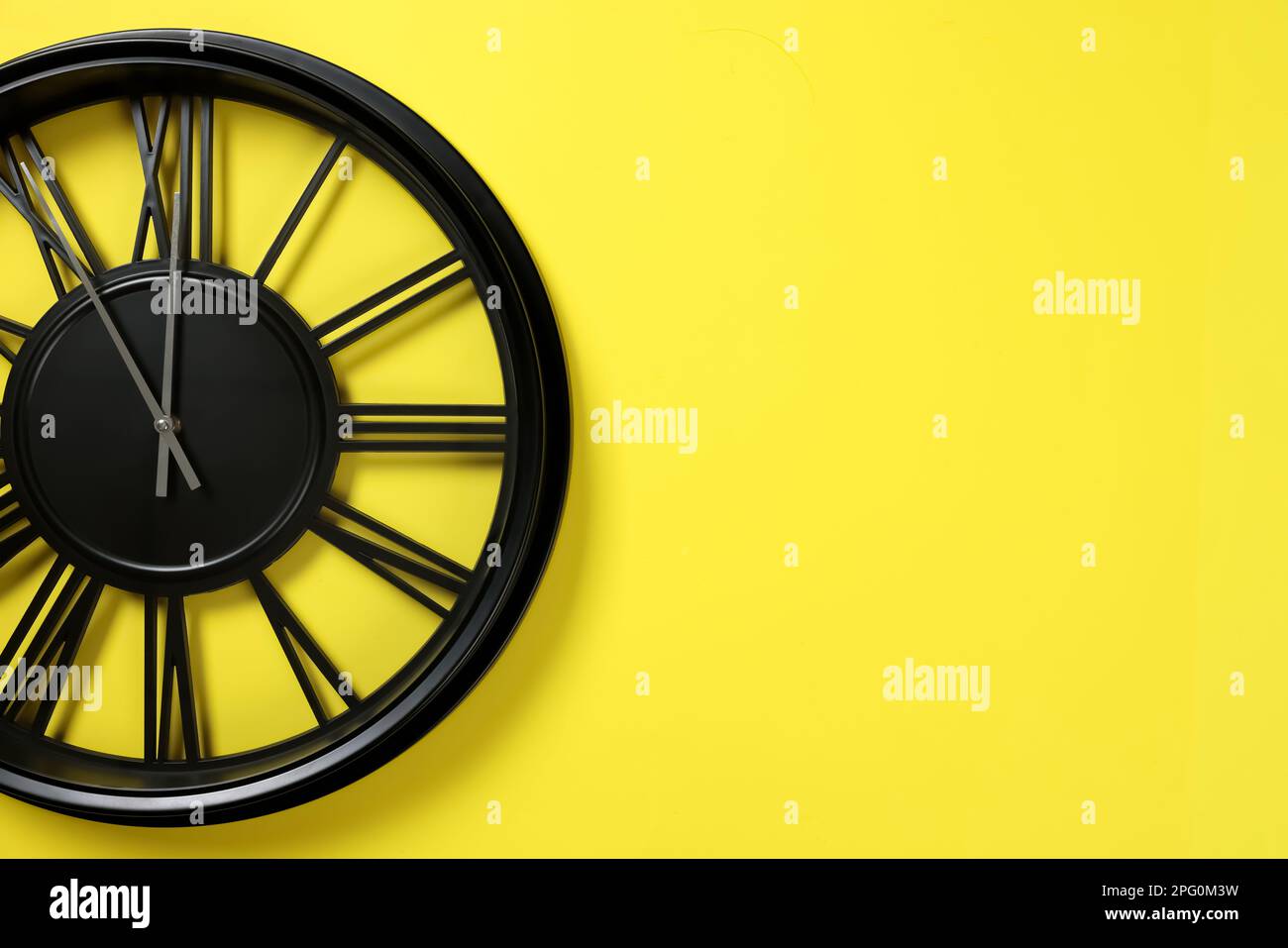 Clock showing five minutes until midnight on yellow background, space ...