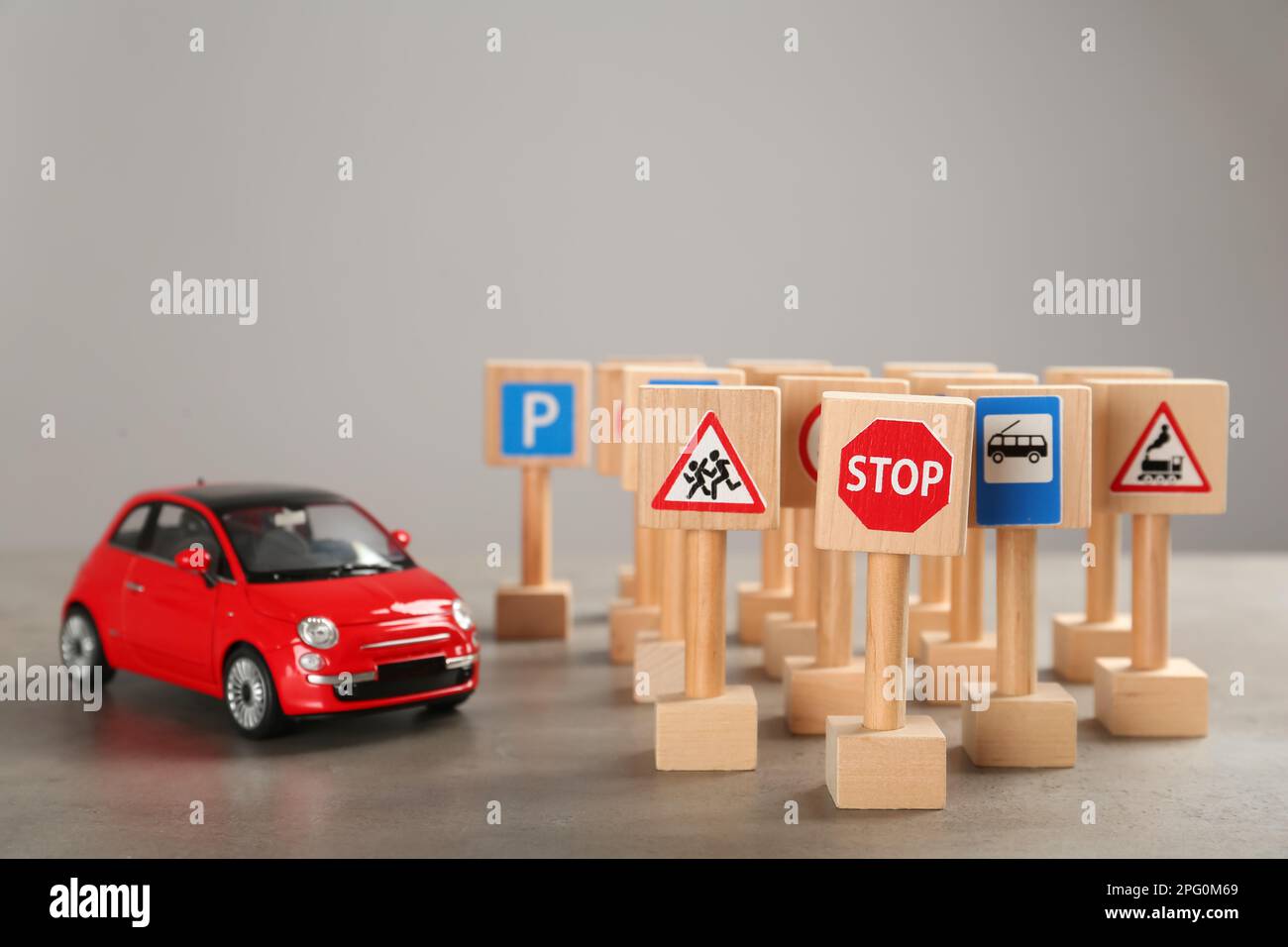 Many different miniature road signs and car on grey table, space for ...
