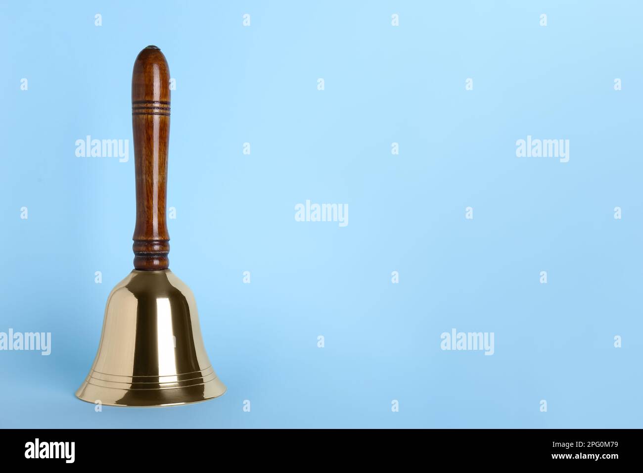 Golden school bell with wooden handle on light blue background. Space ...