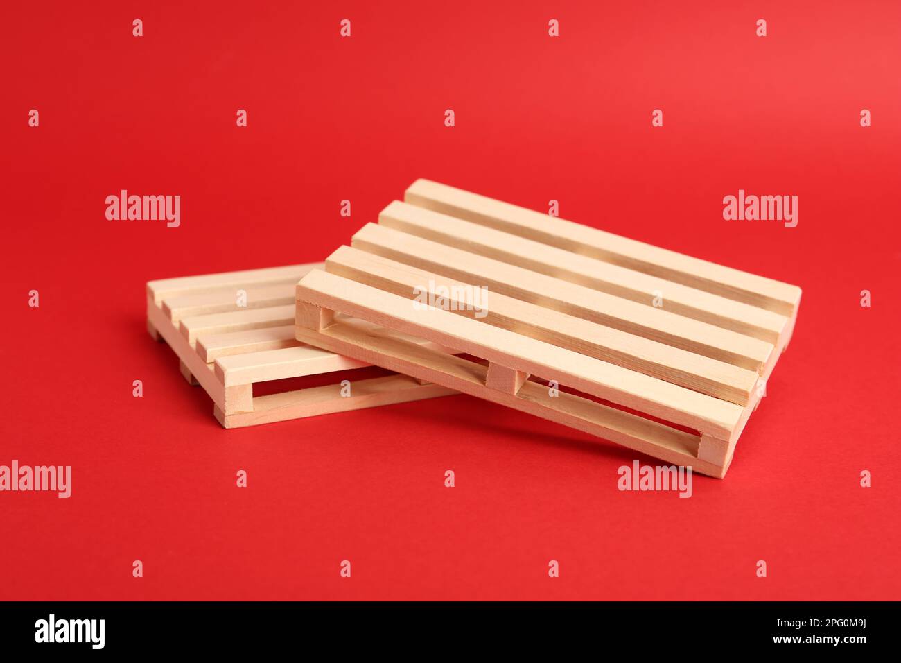 Two small wooden pallets on red background Stock Photo - Alamy