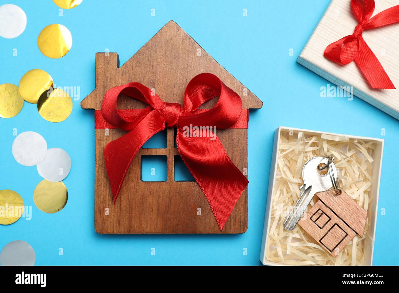 Wooden house model with red bow and key on light blue background, flat ...