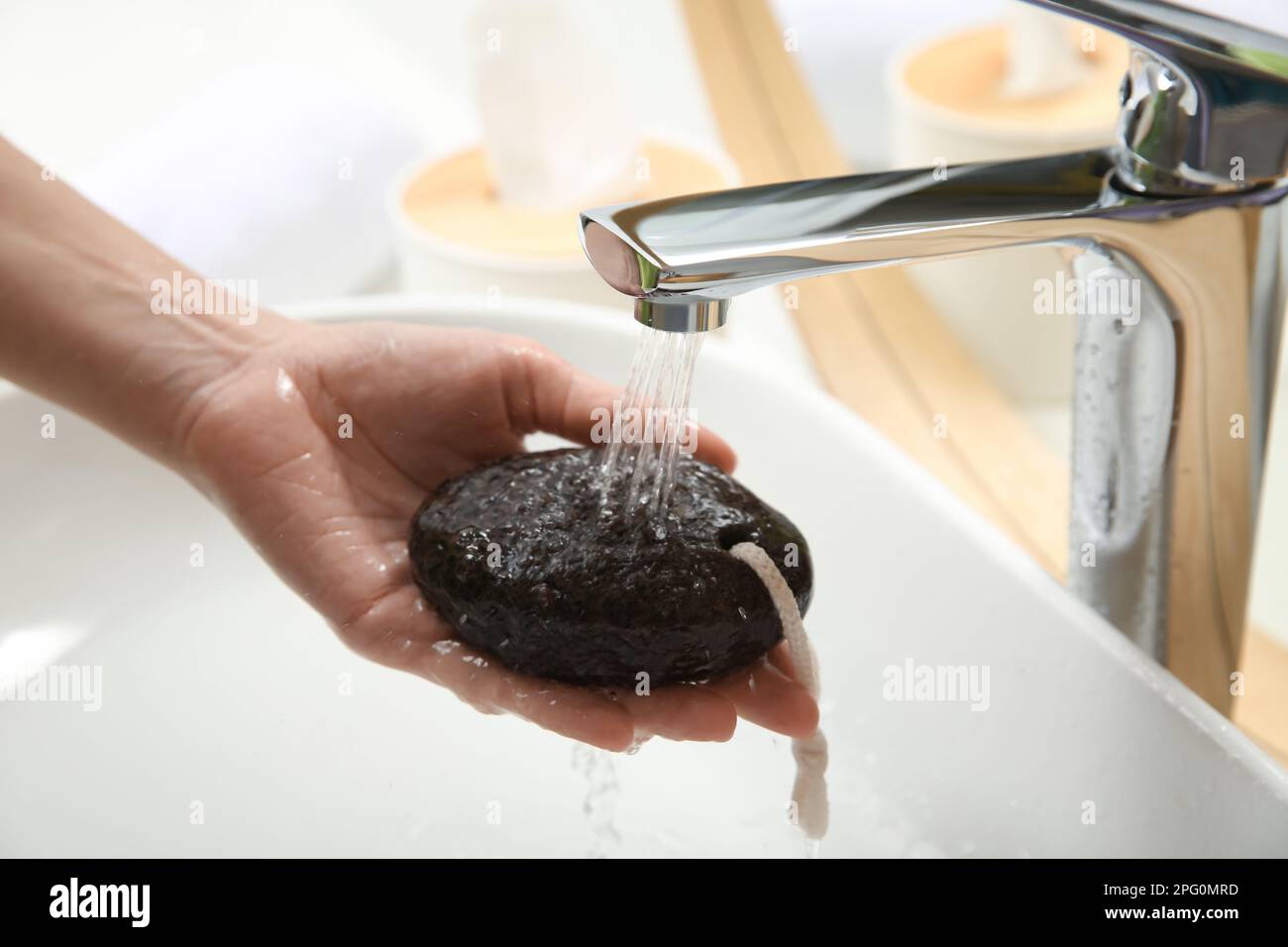 Woman pouring water onto pumice stone in bathroom, closeup Stock Photo ...