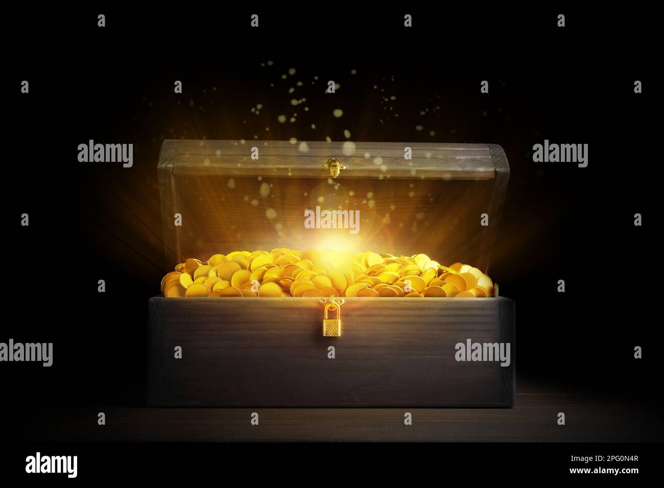 Open treasure chest with gold coins on wooden table against black ...