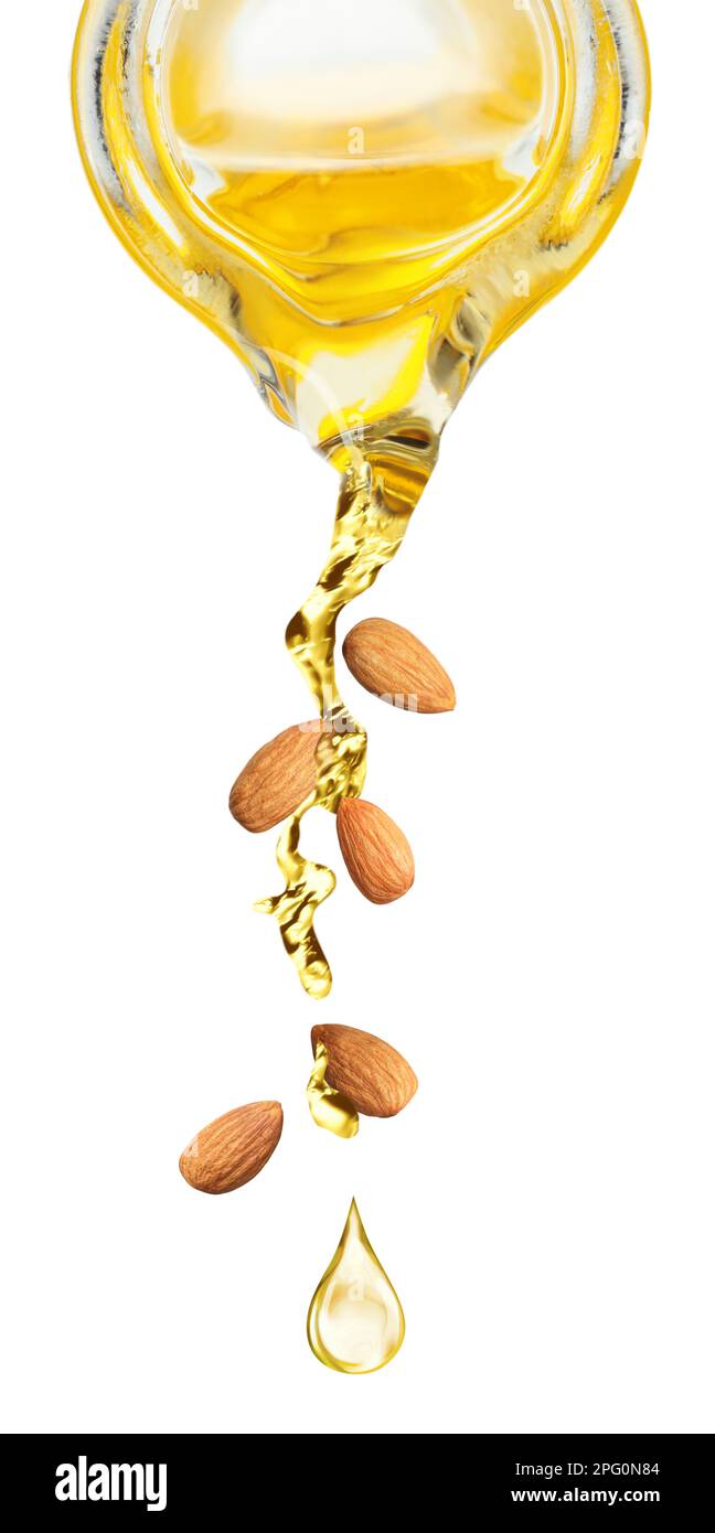 Pouring organic almond oil from glass pitcher and falling nuts on white ...