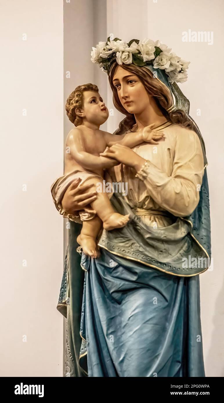Statue of Mary and the baby Jesus celebrating Mary in the month of May with a crown of flowers ...