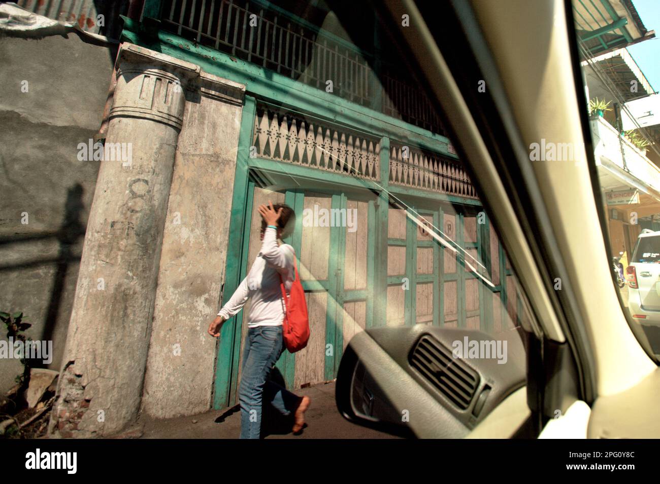 A pedestrian is walking on roadside walkway, in a background of a semi ...