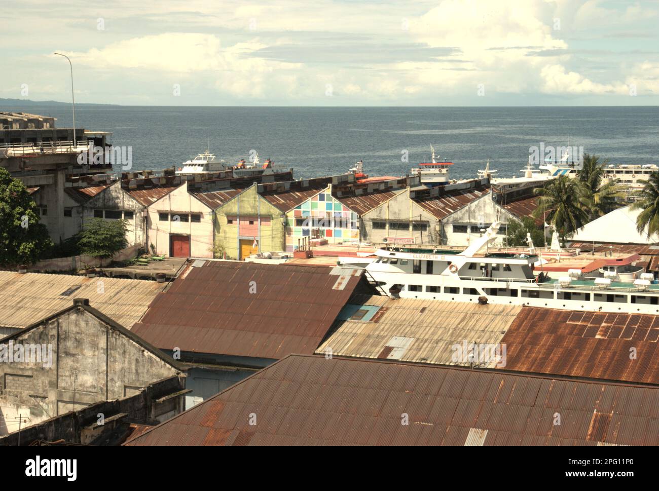 Bay of Manado, ferry boats, a line of warehouses at ferry port, and ...