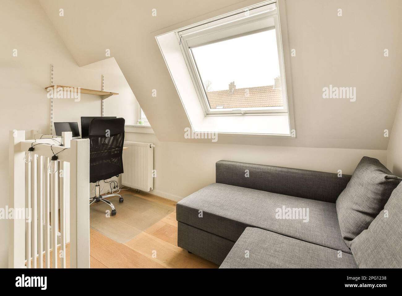 a living room with a couch and computer on the desk in it's corner ...