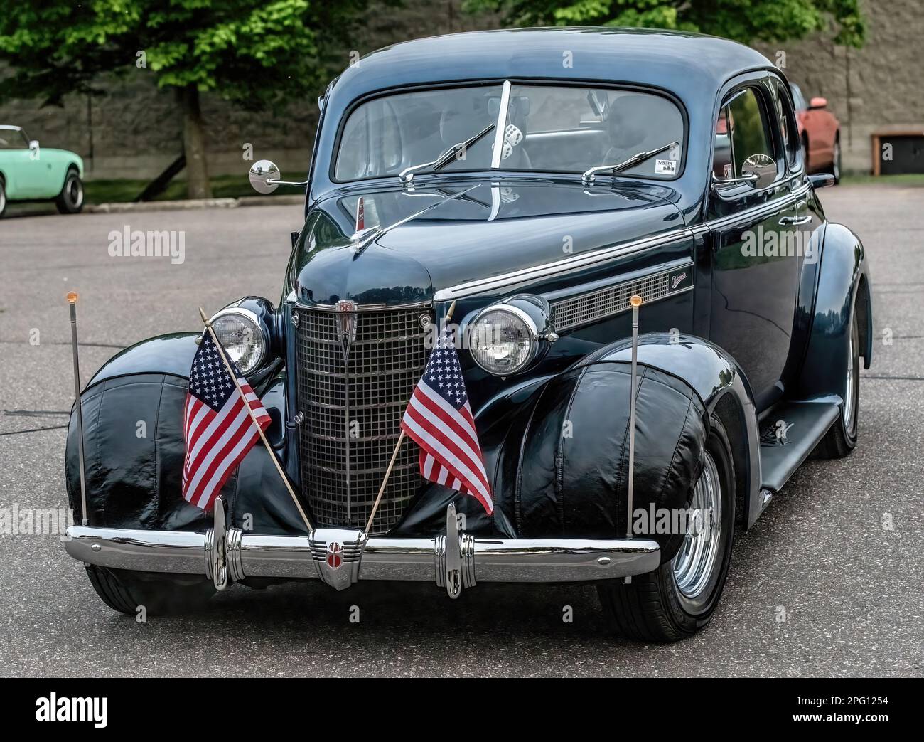1937 GM Oldsmobile Coupe with American flags on a spring evening in ...