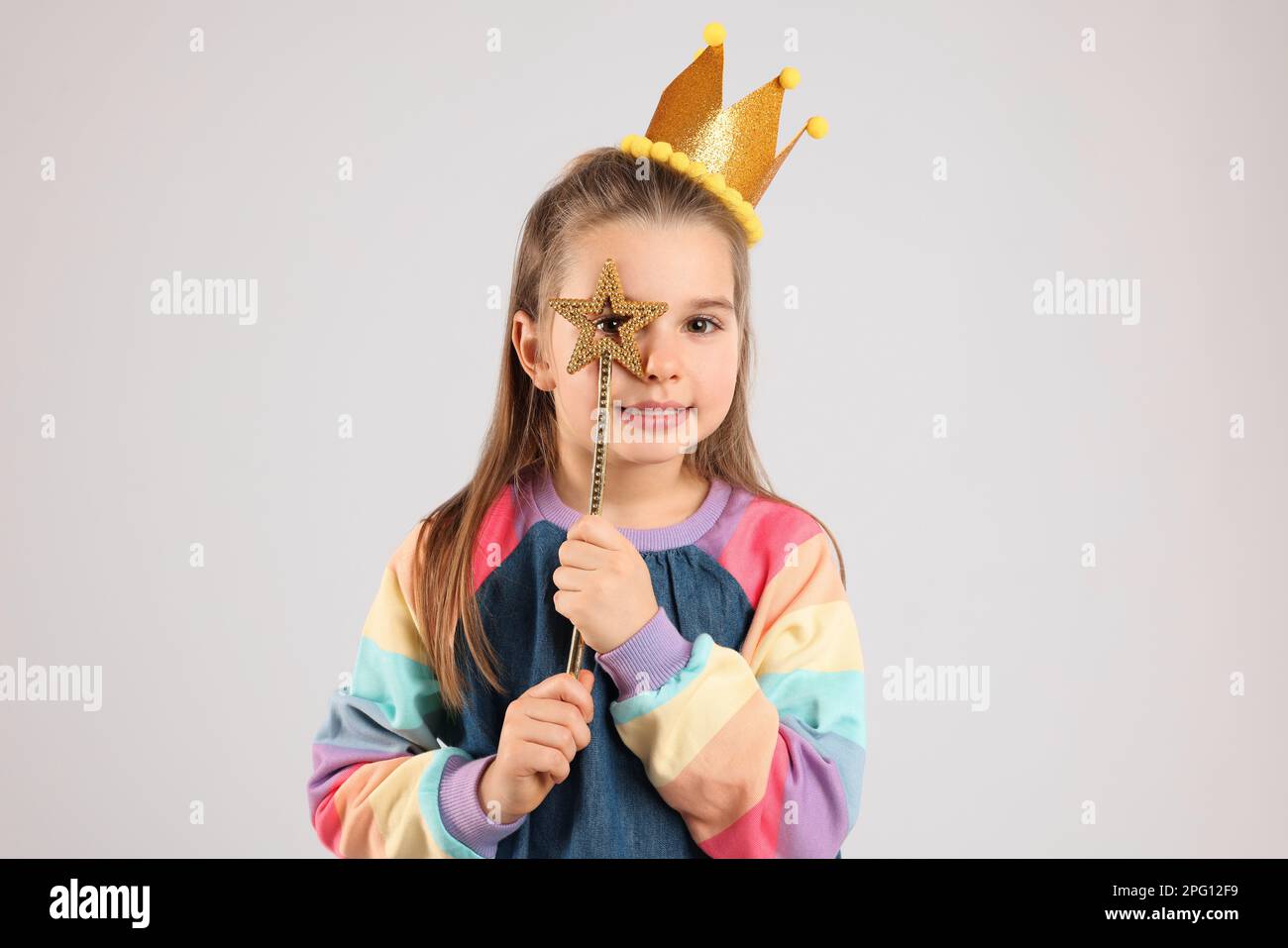 Cute girl in golden crown with magic wand on light grey background ...