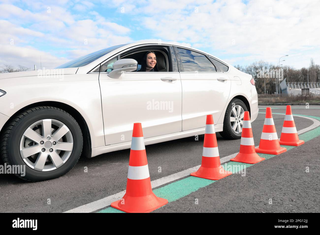 Young woman in car on test track with traffic cones. Driving school ...