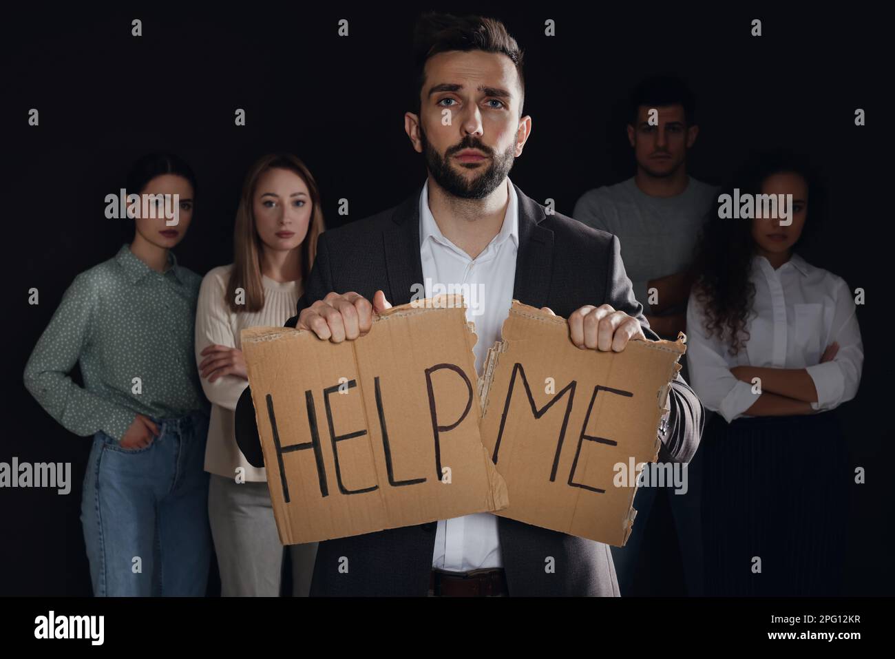 Unhappy man with HELP ME sign and group of people behind his back on ...
