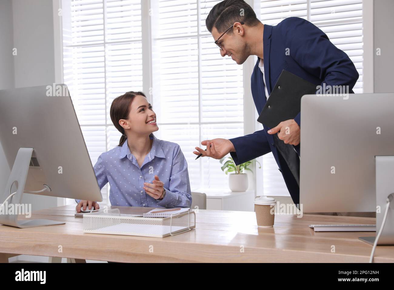Businessman helping intern with work in office Stock Photo - Alamy