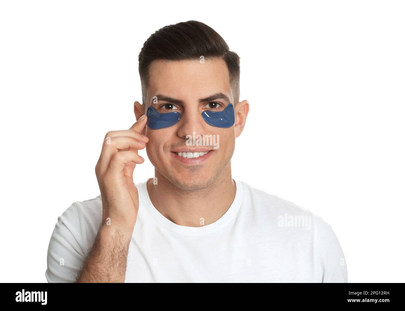 Man applying blue under eye patch on white background Stock Photo - Alamy