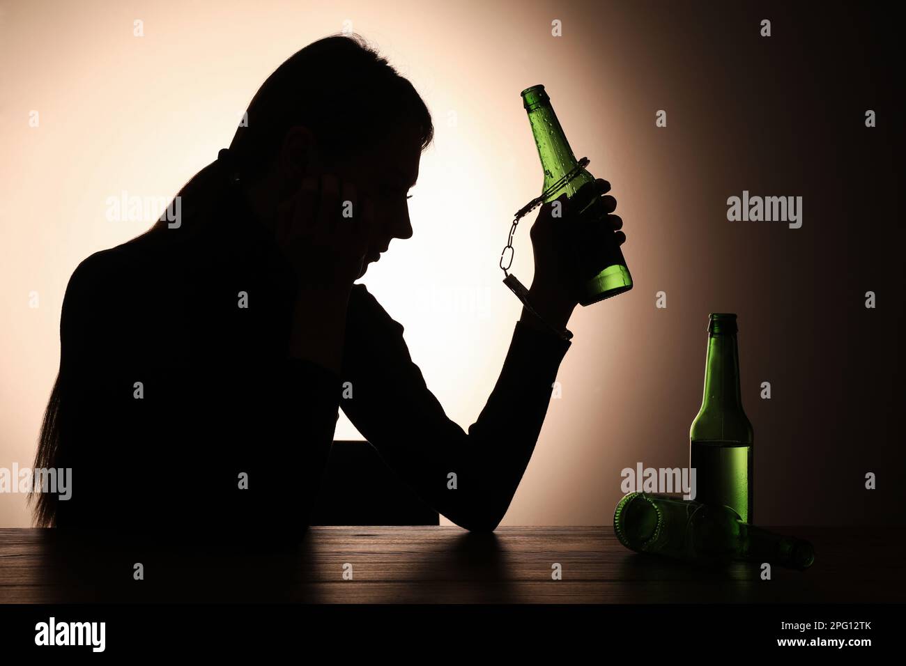 Alcohol addiction. Silhouette of woman handcuffed with beer bottle at ...