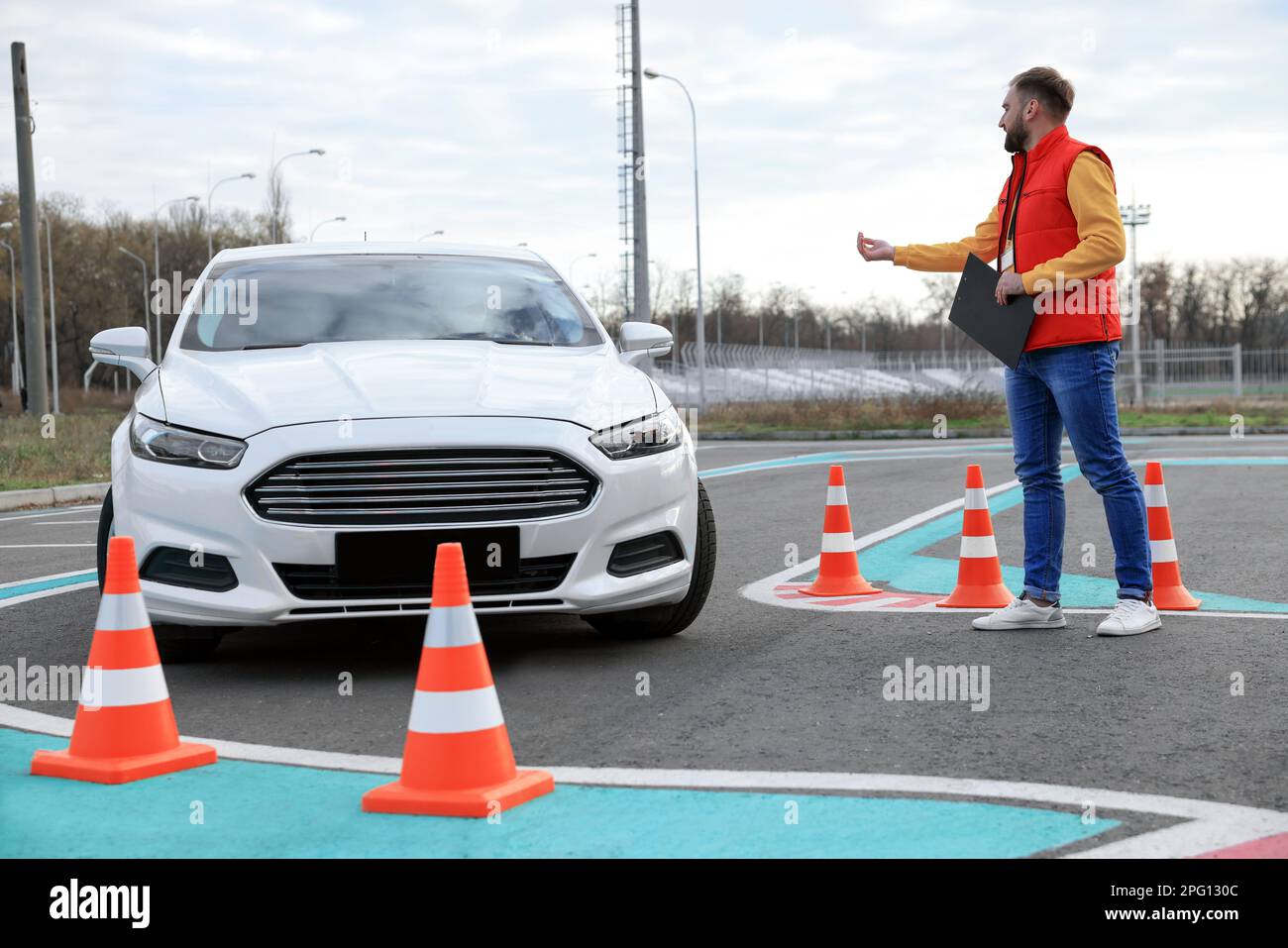 Instructor near car with his student during exam at driving school test ...