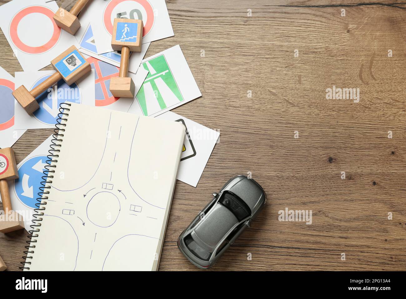 Many different road signs, notebook and toy car on wooden background ...
