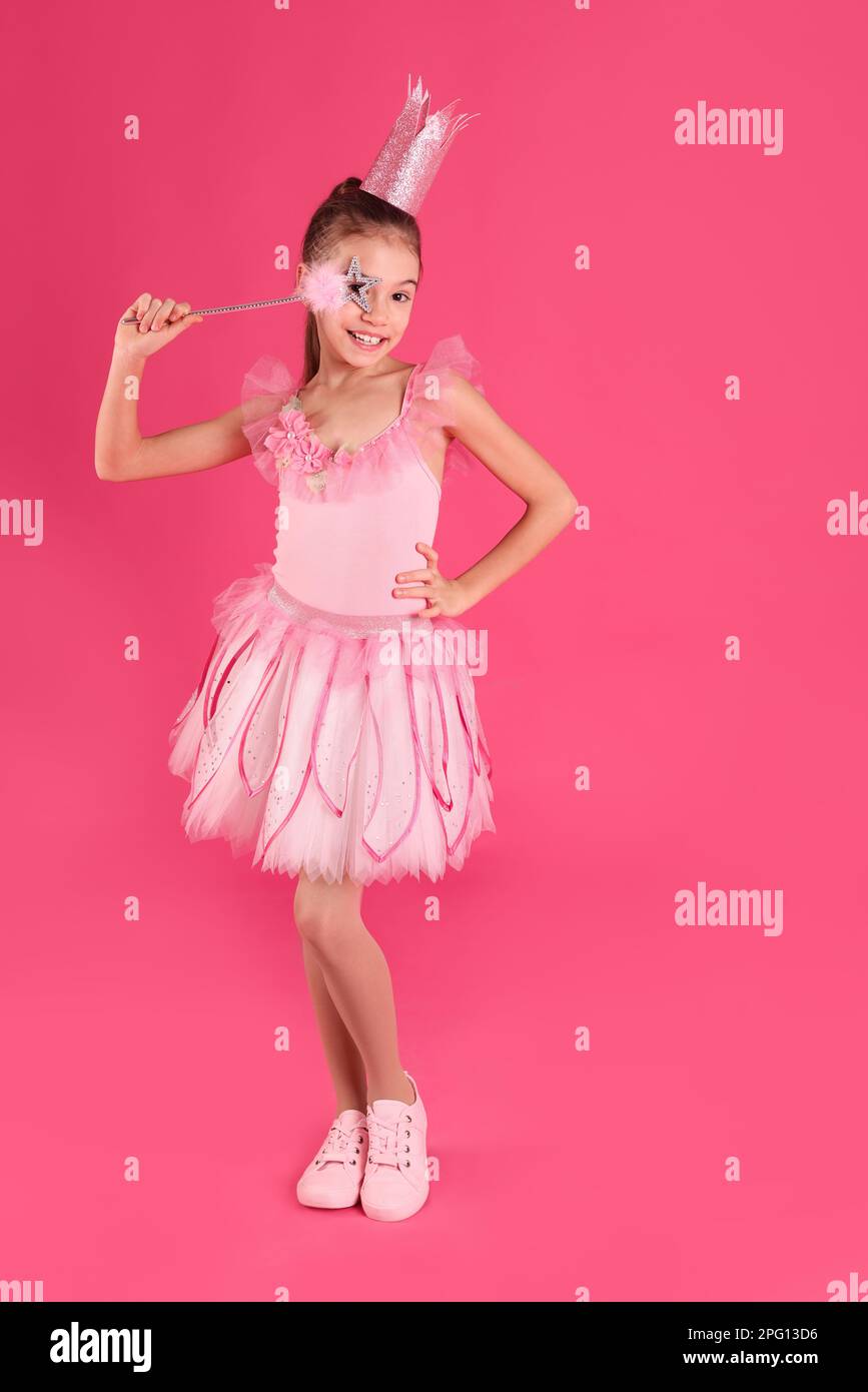 Cute girl in fairy dress with crown and magic wand on pink background ...