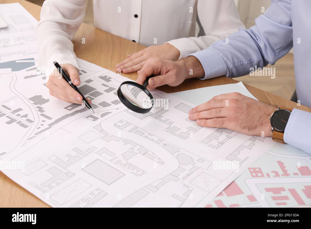 Professional cartographers working with cadastral map at table, closeup ...