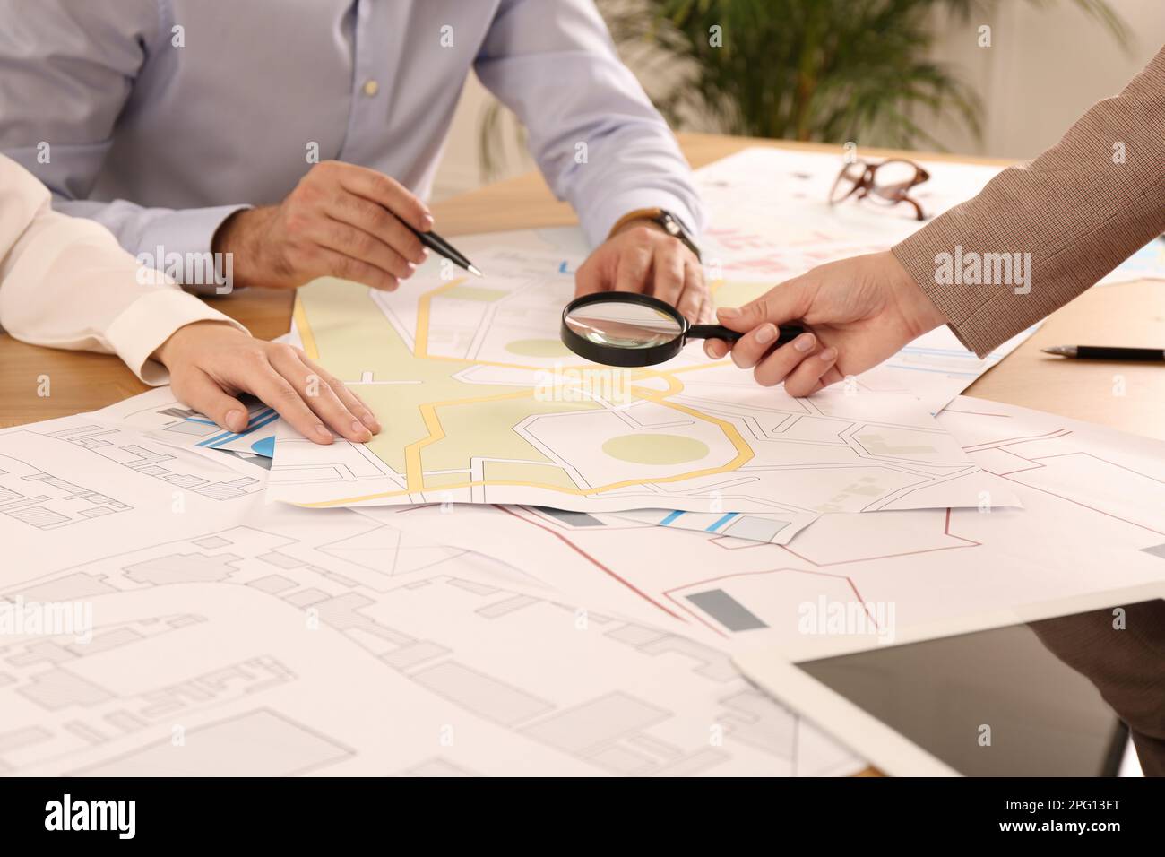 Professional cartographers working with cadastral map at table in ...