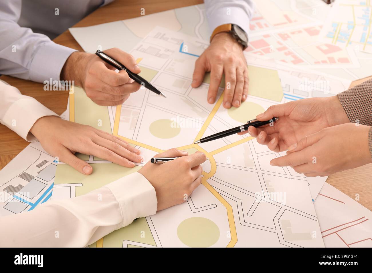 Professional cartographers working with cadastral map at table, closeup ...