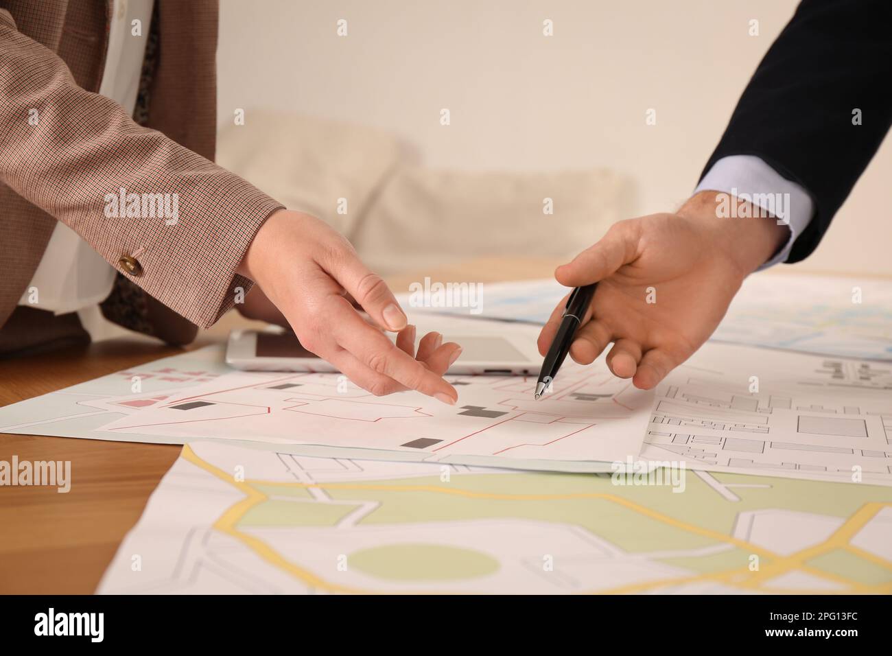 Professional cartographers working with cadastral map at table in ...