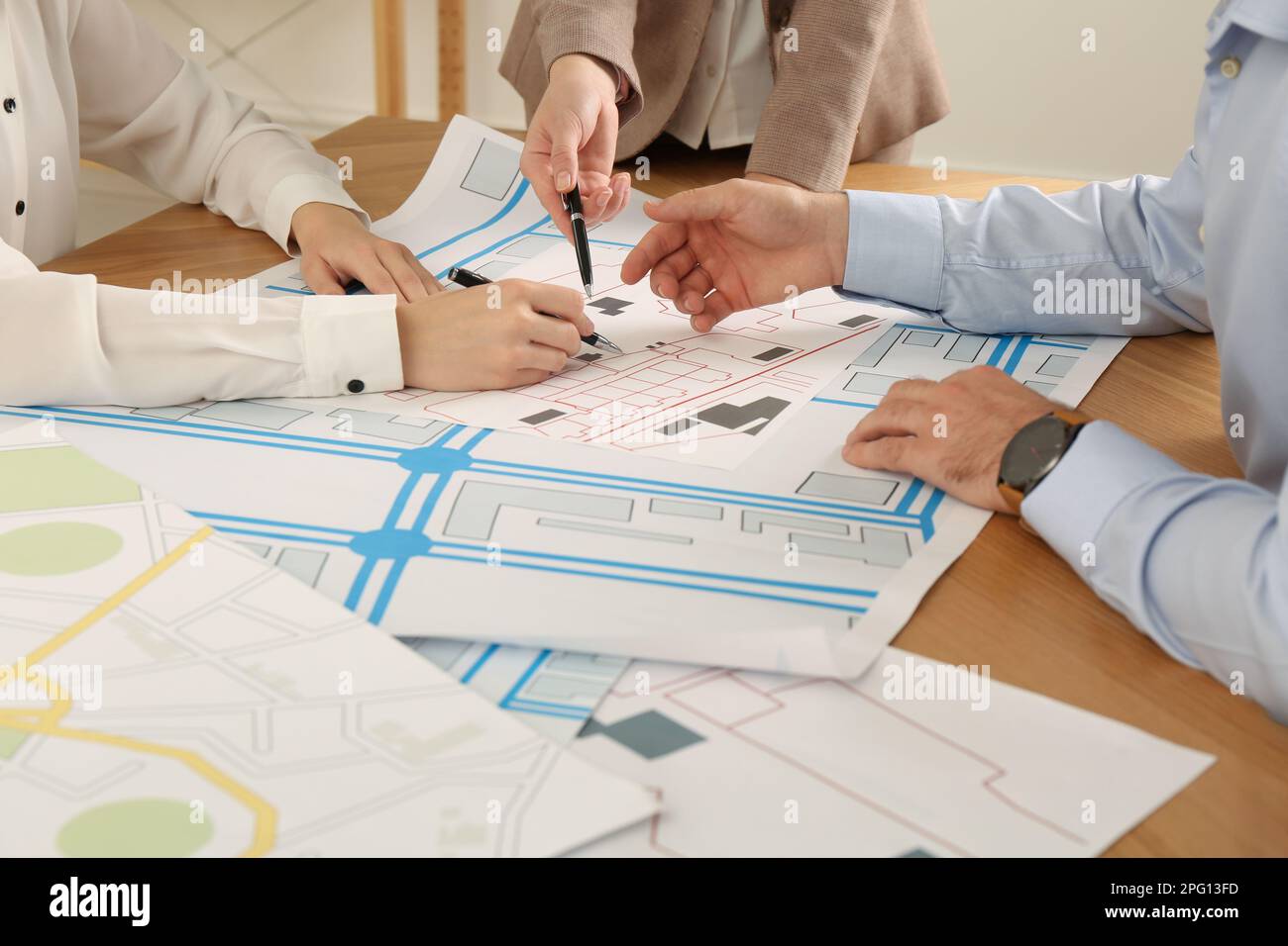 Professional cartographers working with cadastral map at table, closeup ...