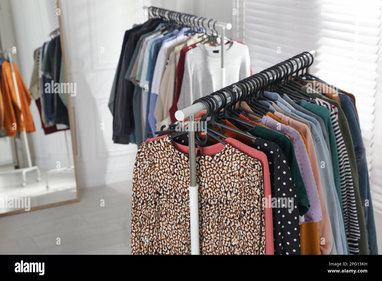 Racks with stylish clothes indoors. Fast fashion Stock Photo - Alamy
