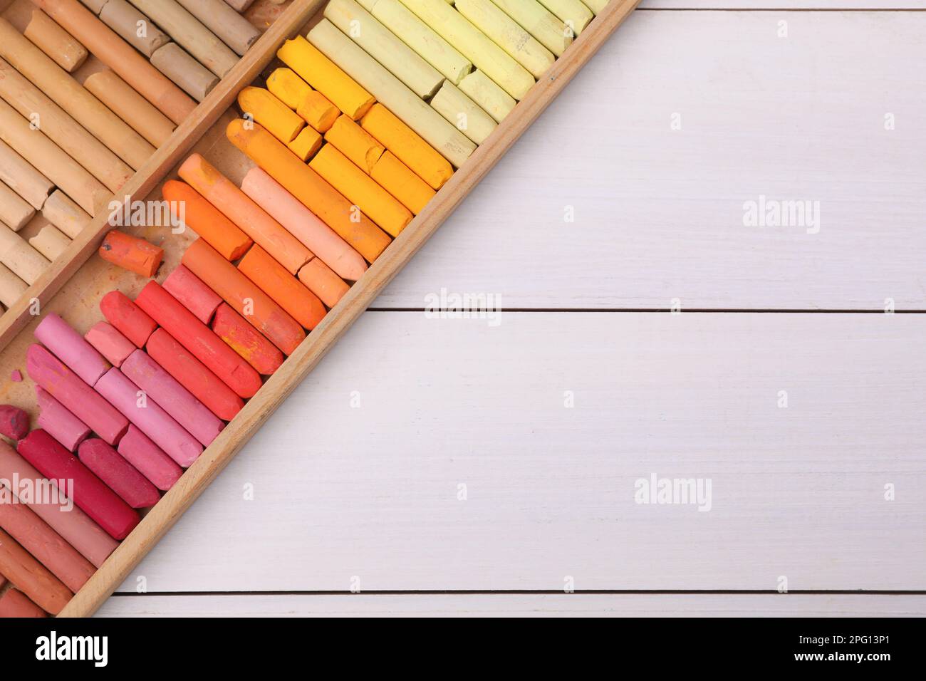 Set of soft pastels in box on white wooden table, top view with space ...