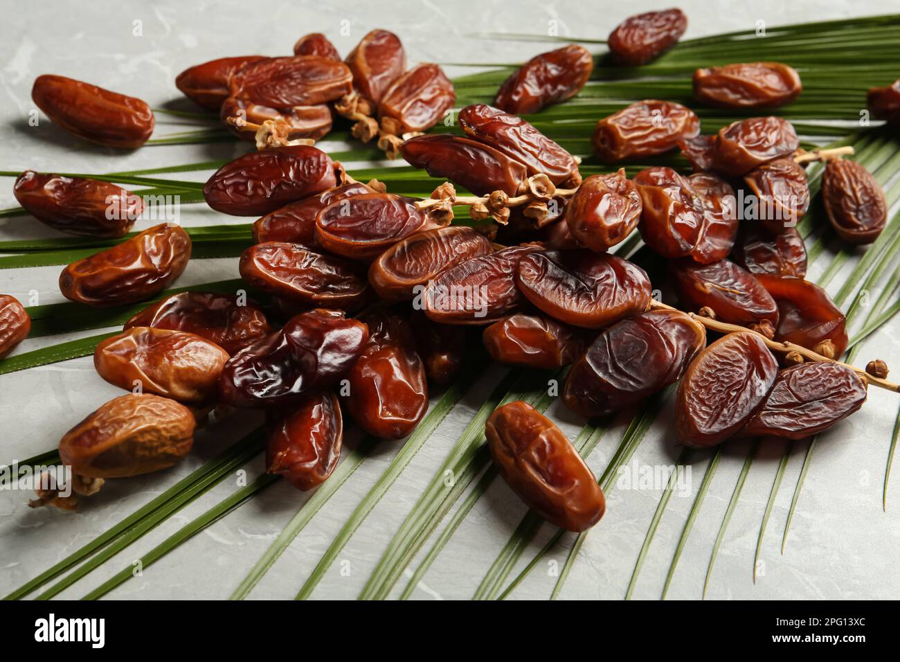 Tasty sweet dried dates and palm leaf on light table Stock Photo - Alamy