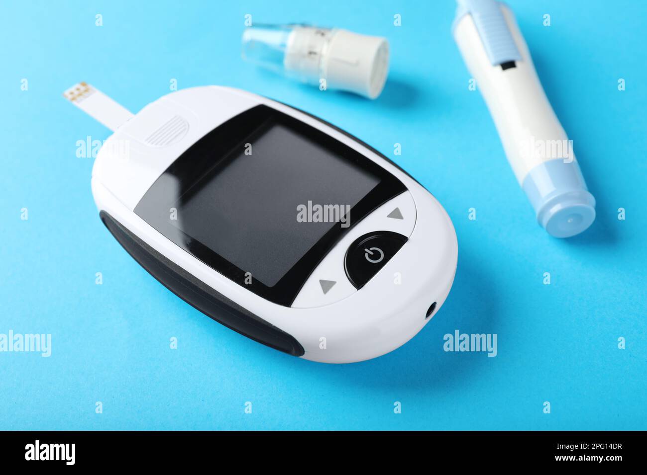 Digital glucometer and lancet pen on light blue background. Diabetes ...