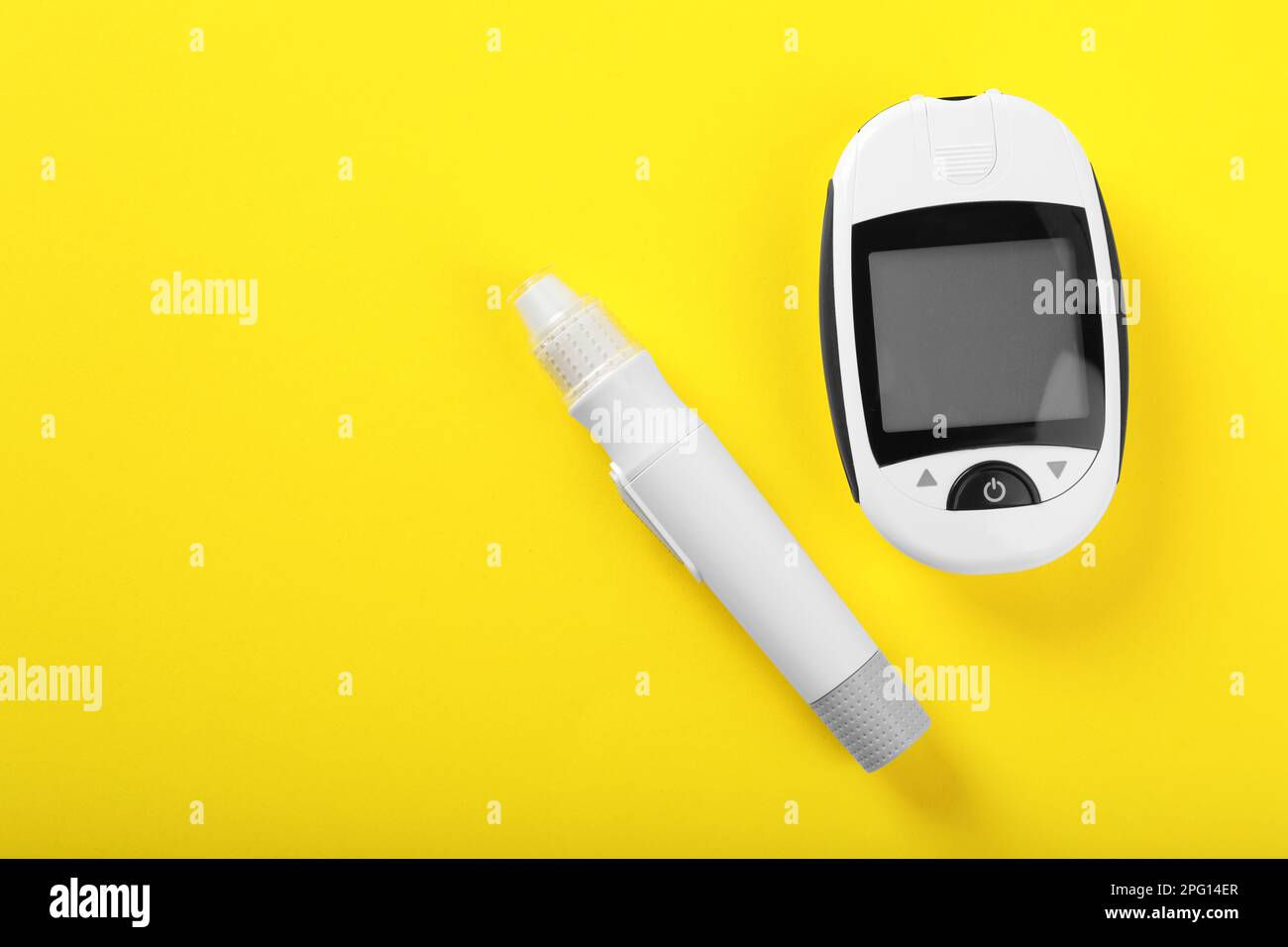Digital glucometer and lancet pen on yellow background, flat lay with ...