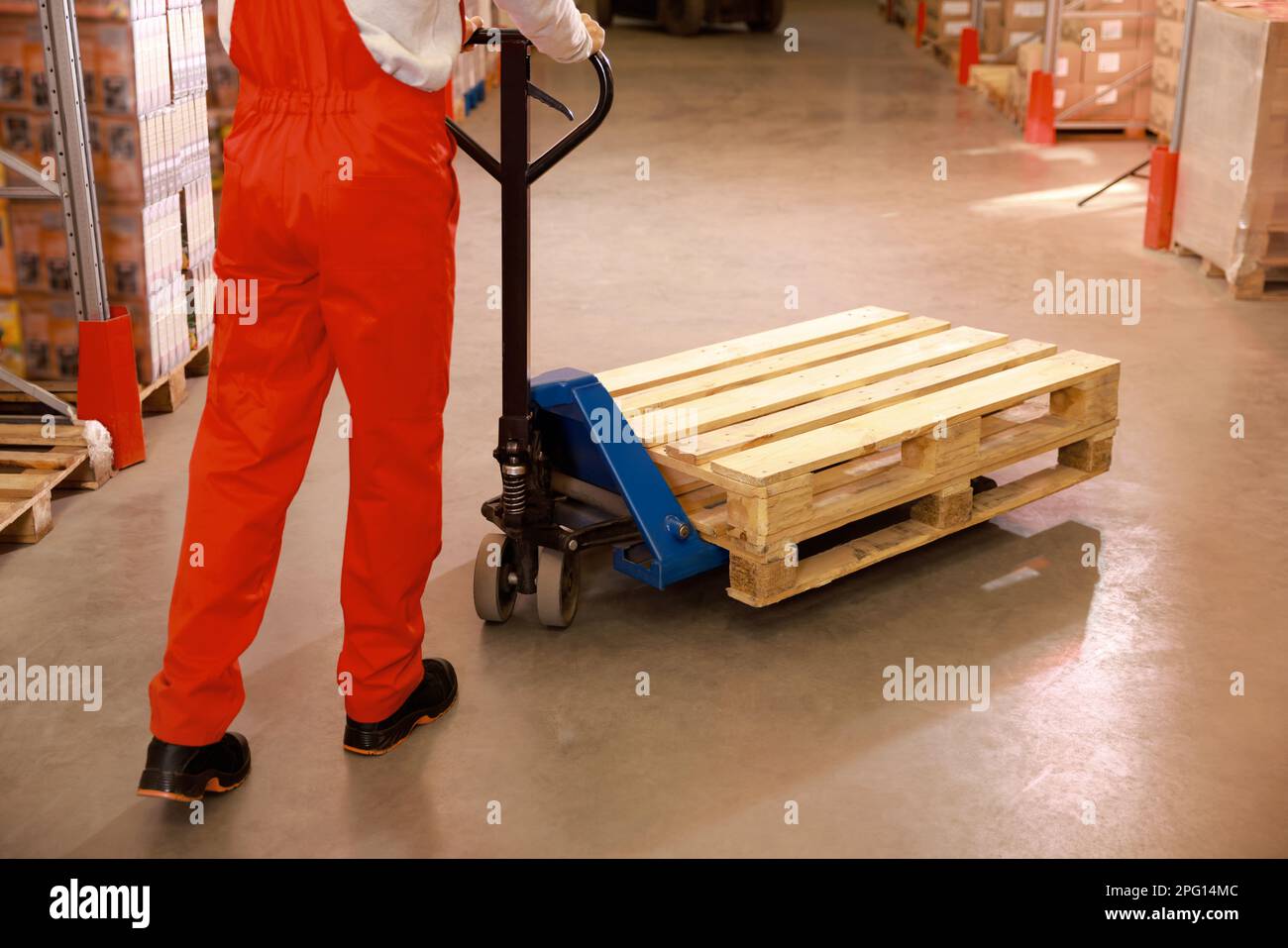 Worker moving wooden pallets with manual forklift in warehouse, closeup ...