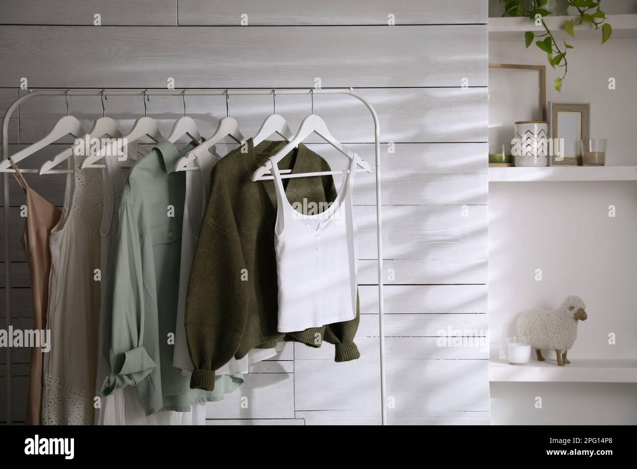 Rack with different stylish clothes near white wall in dressing room ...