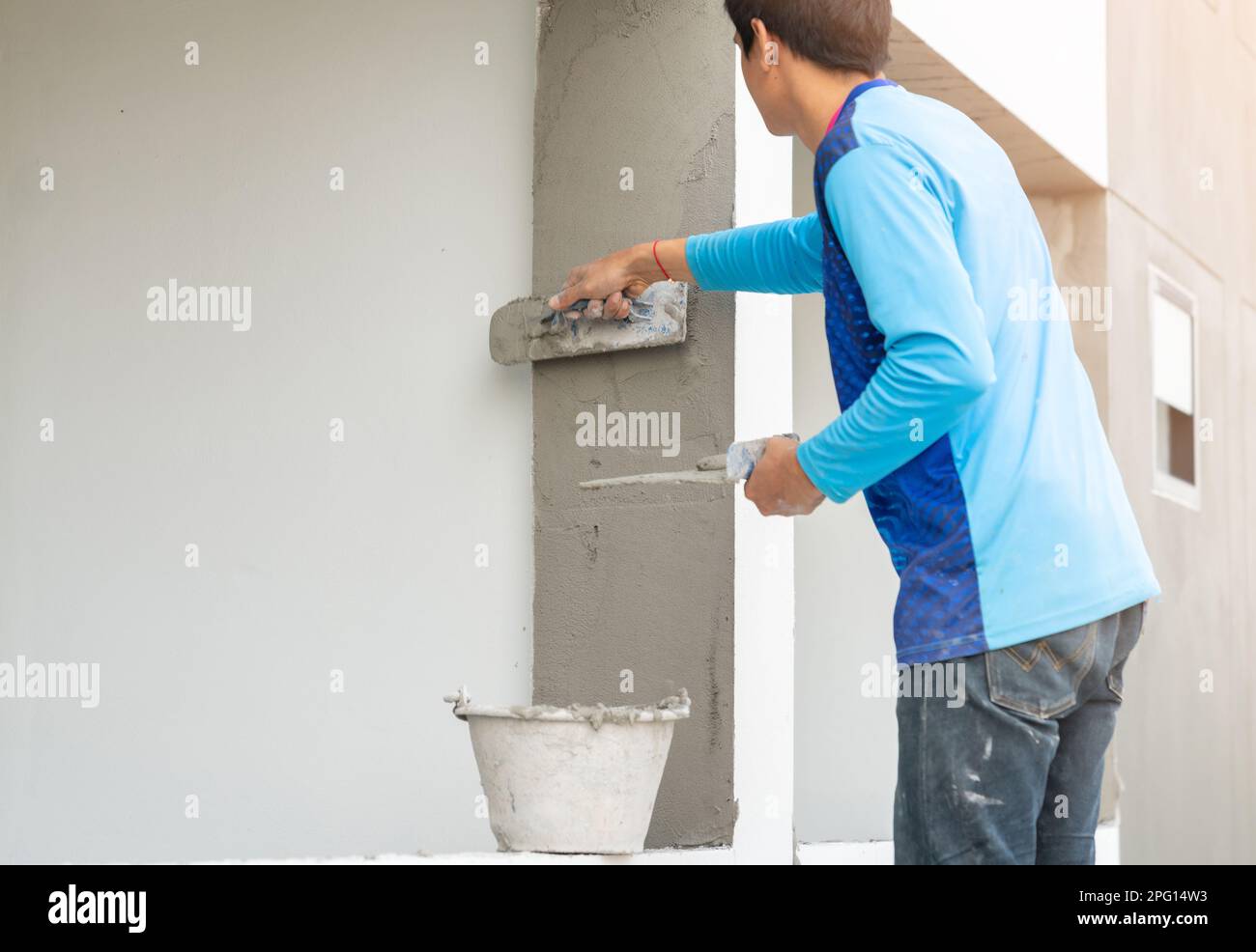 Construction worker plastering a wall with a spatula in construction ...