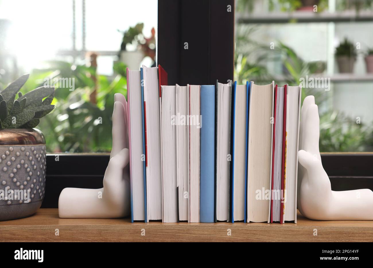 Beautiful hand shaped bookends with books on window sill indoors Stock ...