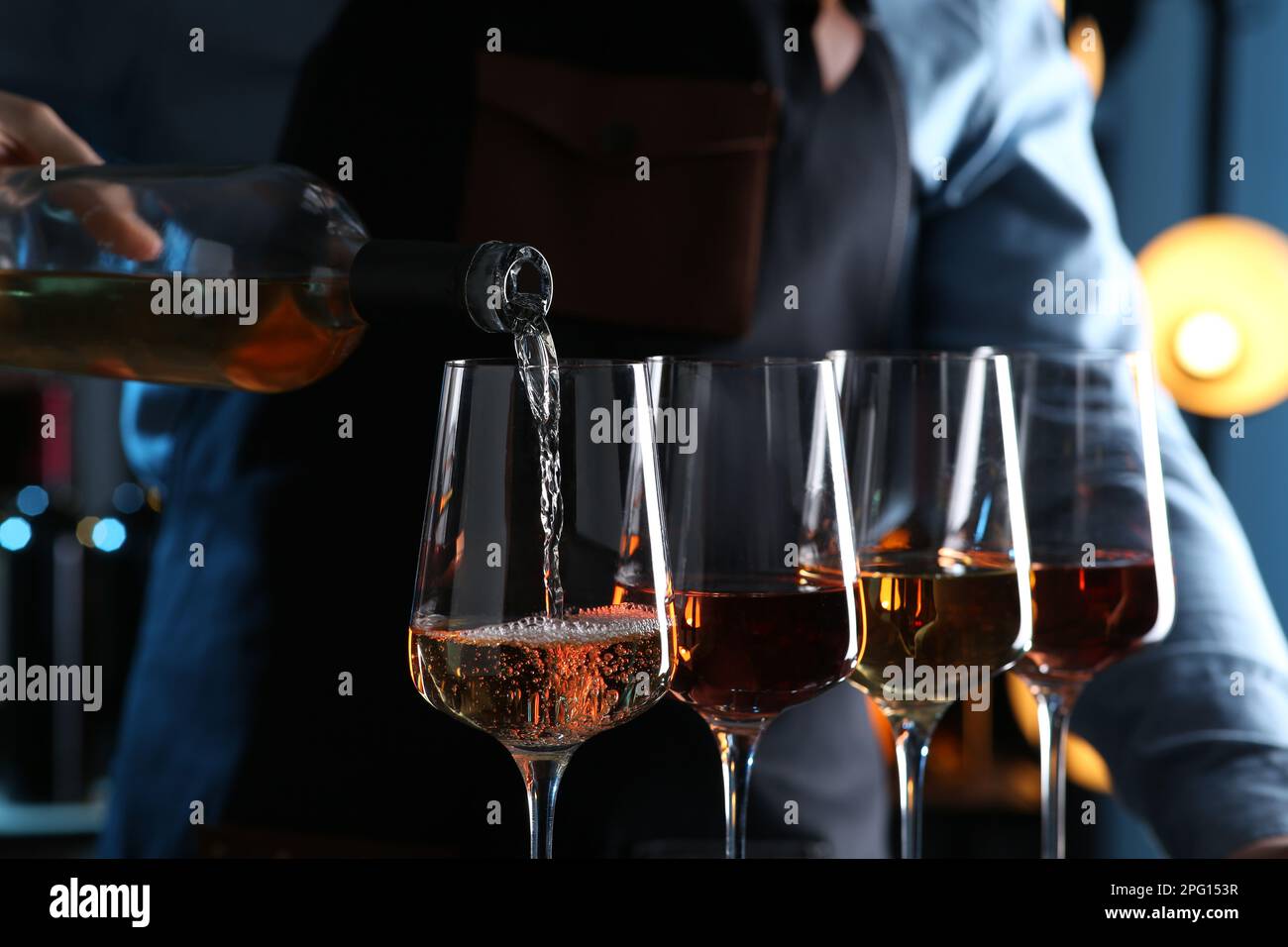 Bartender pouring rose wine from bottle into glass indoors, closeup ...