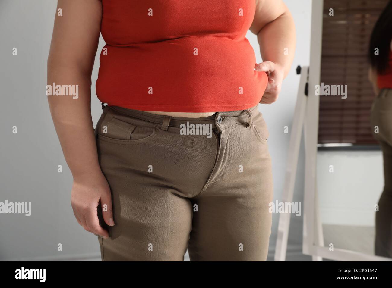 Overweight woman in tight shirt and trousers at home, closeup Stock ...