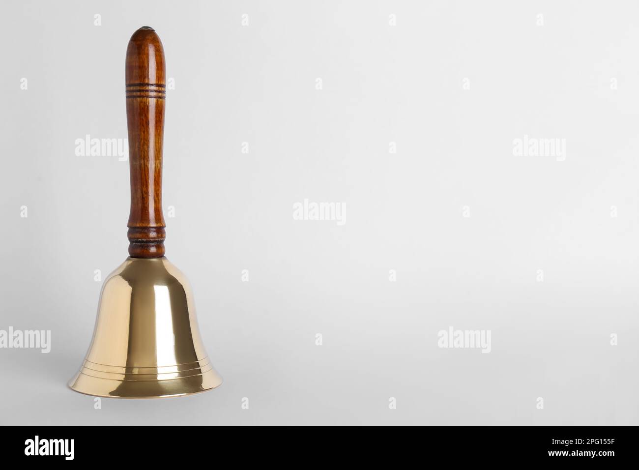 Golden school bell with wooden handle on grey background. Space for ...